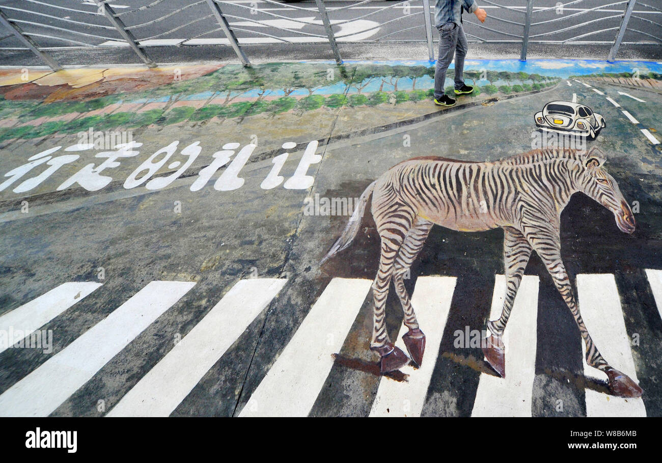 A pedestrian walks on a zebra crossing featuring a 3D painting of a ...