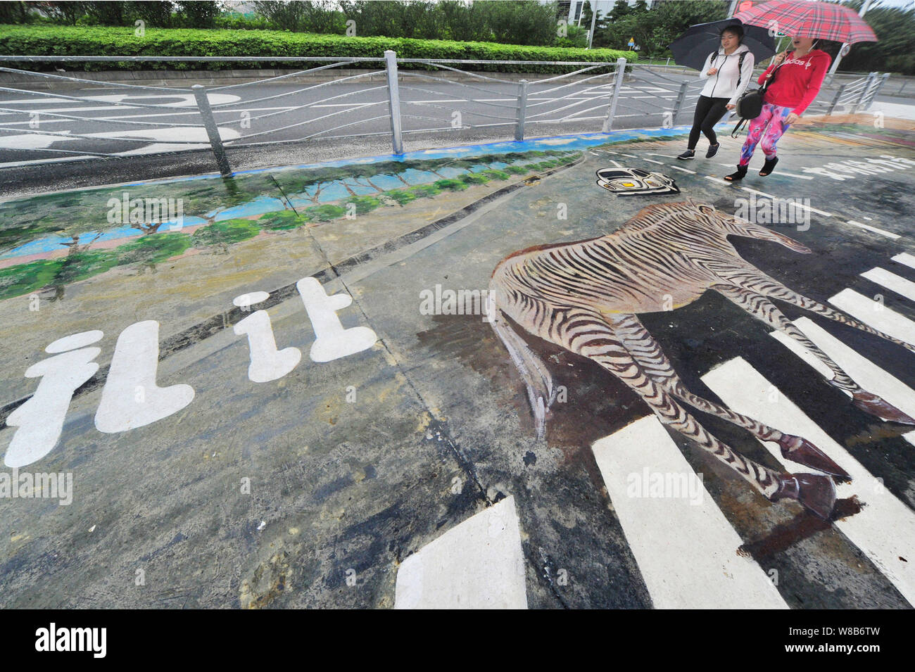 Pedestrians walk on a zebra crossing featuring a 3D painting of a zebra ...