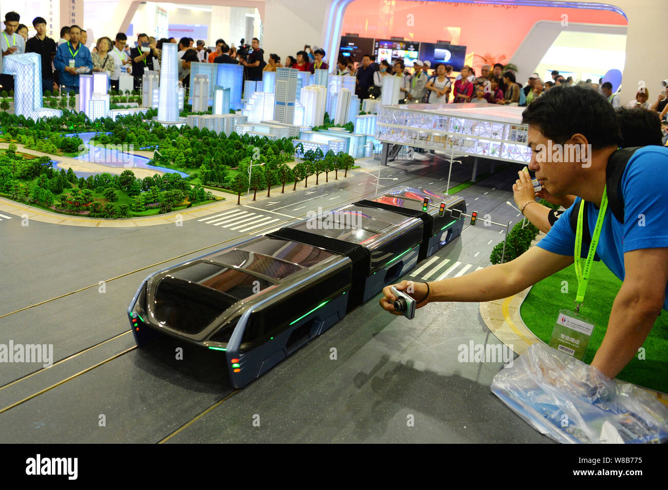 Visitors take photos of a model of the 'Transit Elevated Bus' on ...