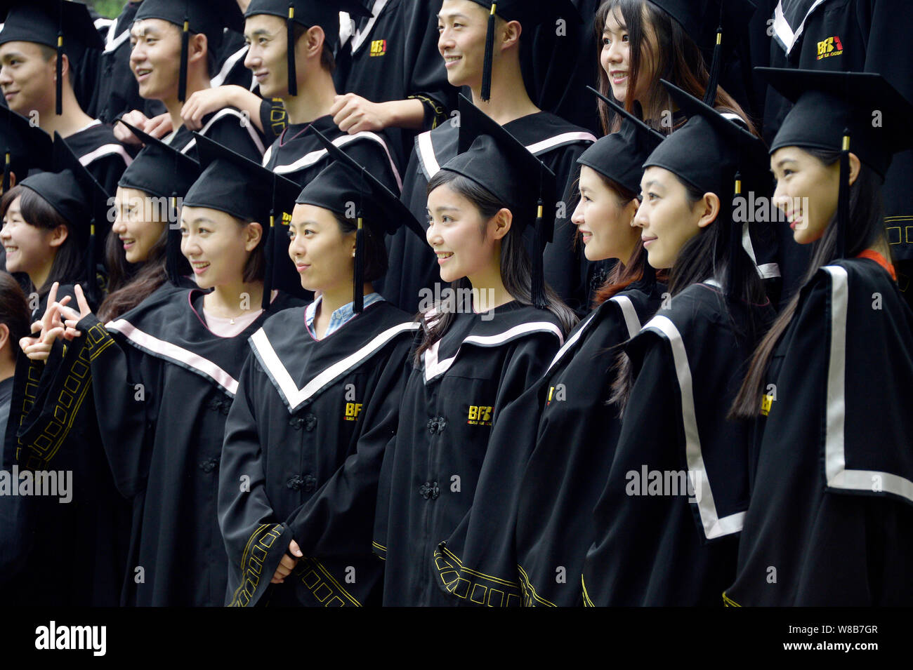 Chinese graduates dressed in academic gowns pose during a graduation ...