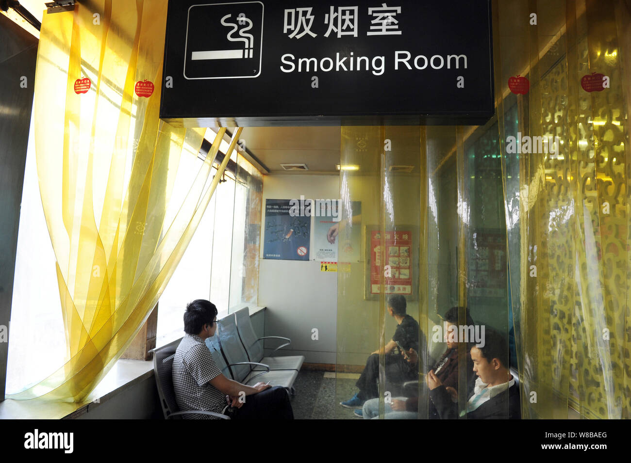 Chinese passengers smoke cigarettes in a smoking room at the Chengdu ...
