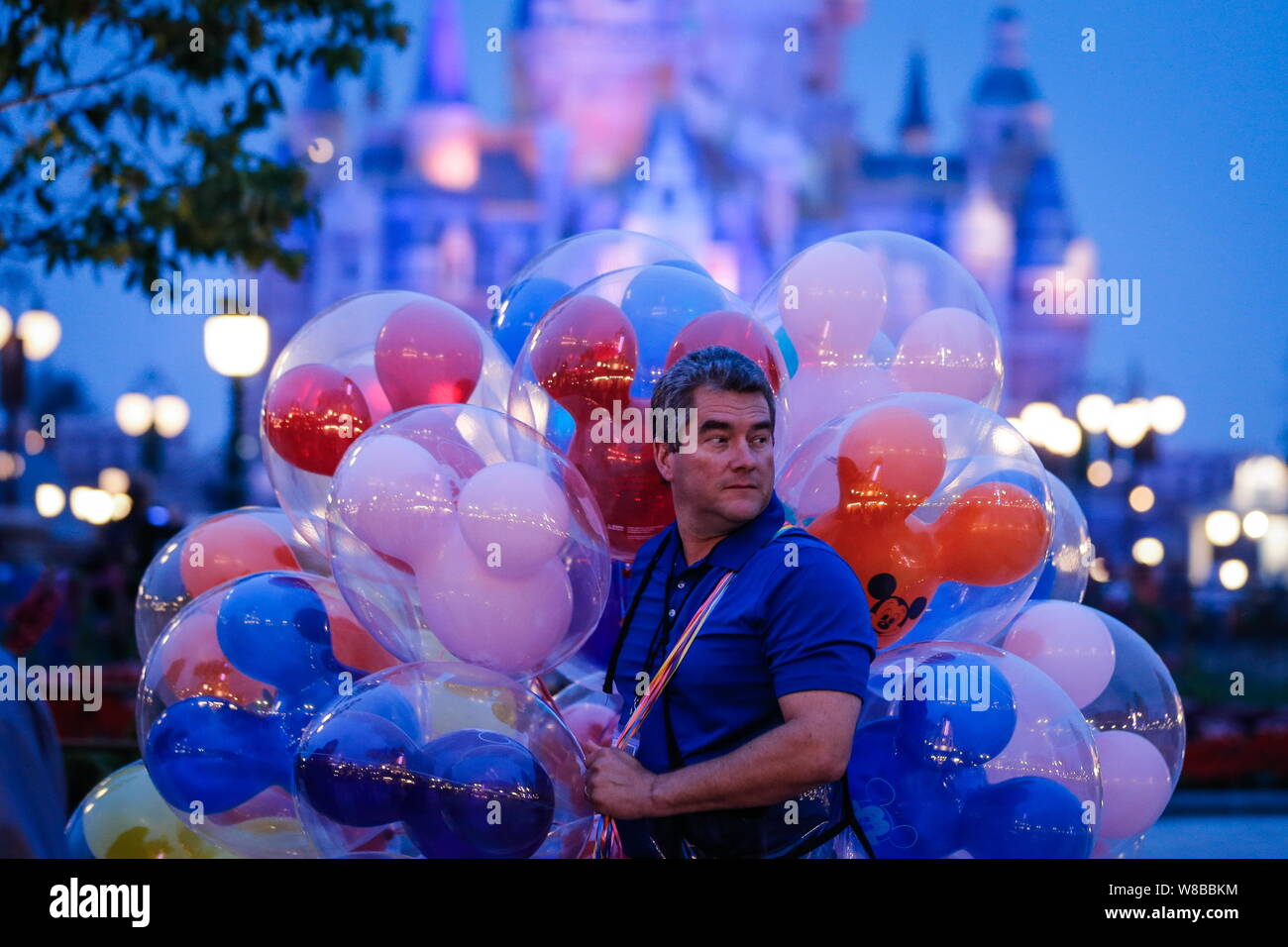 An employee sells Mickey Mouse balloons in Disneytown at the Shanghai ...