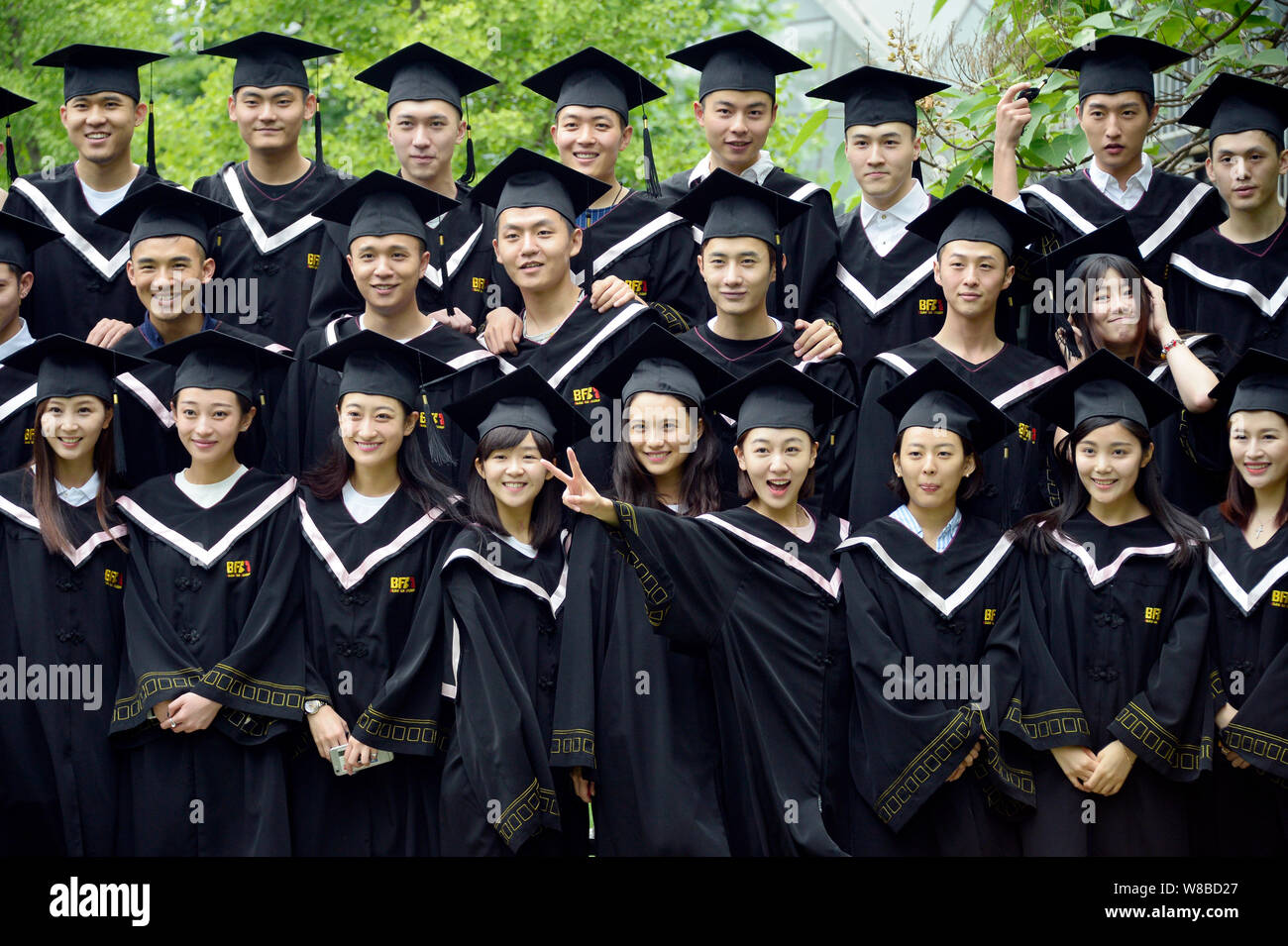 Chinese graduates dressed in academic gowns pose during a graduation ...