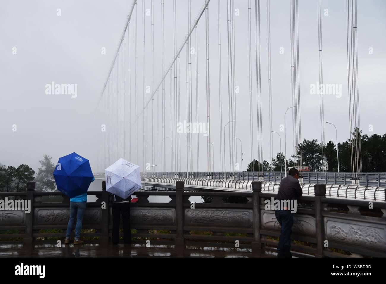Visitors look at the Longjiang Grand Bridge enveloped by mist and cloud ...