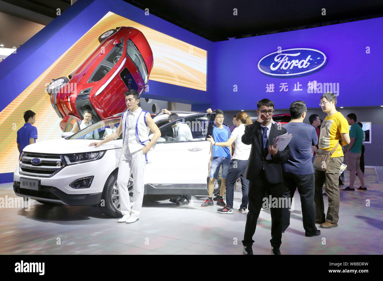 --FILE--Visitors try out or look at a Ford Edge SUV on display during ...