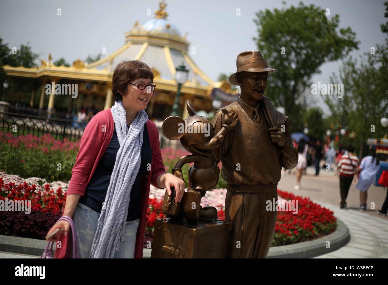 A tourist poses for photos with a Mickey Mouse-themed statue the ...