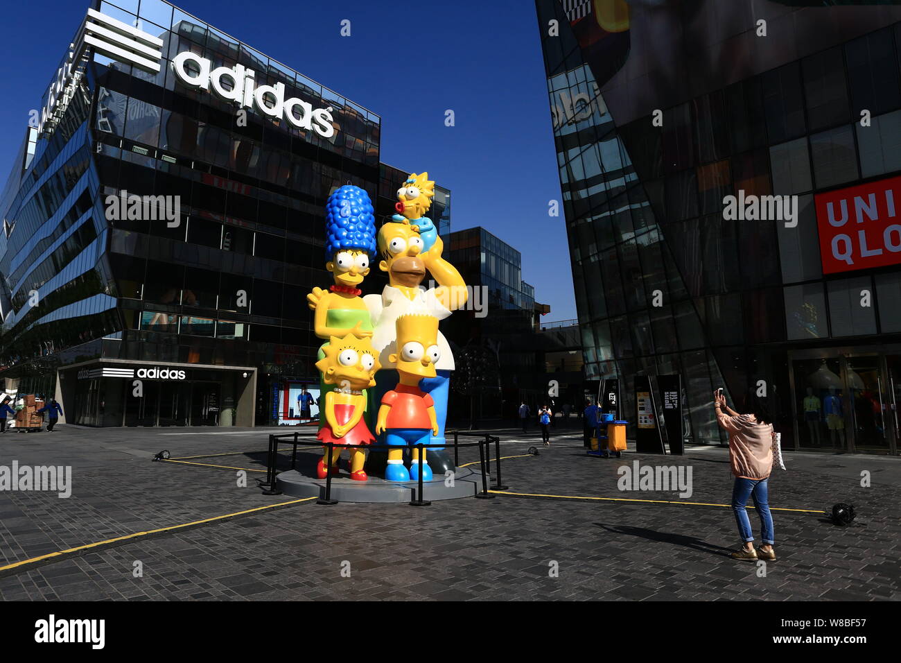 A young woman takes pictures of model figures of The Simpsons on ...