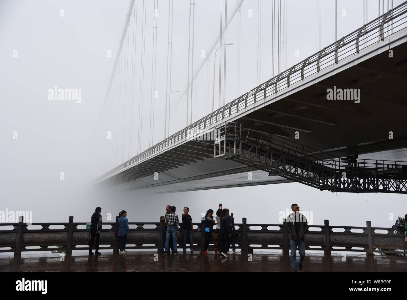 Visitors look at the Longjiang Grand Bridge enveloped by mist and cloud ...