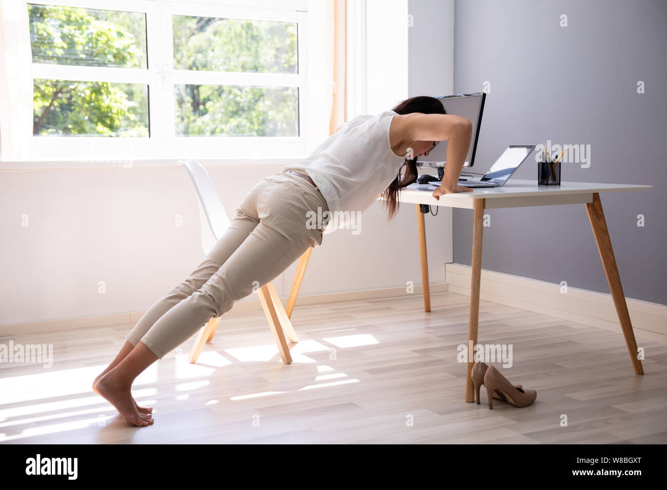 Side View Of A Young Businesswoman Doing Push Up On Office Desk Stock ...