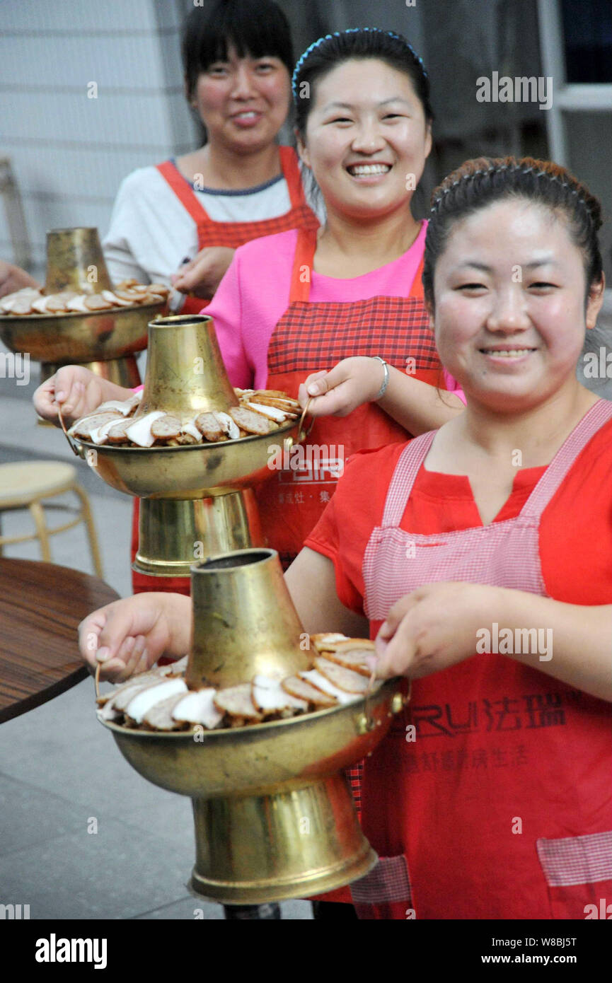 --FILE--Chinese waitresses carry food-stuffed hot pots at a hotpot ...
