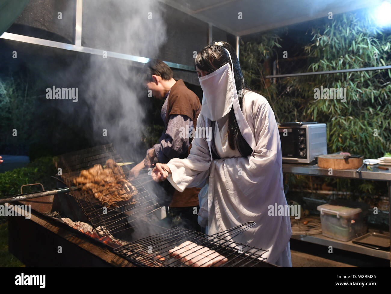 Chinese waiter and waitress wearing ancient Chinese costumes barbecue ...