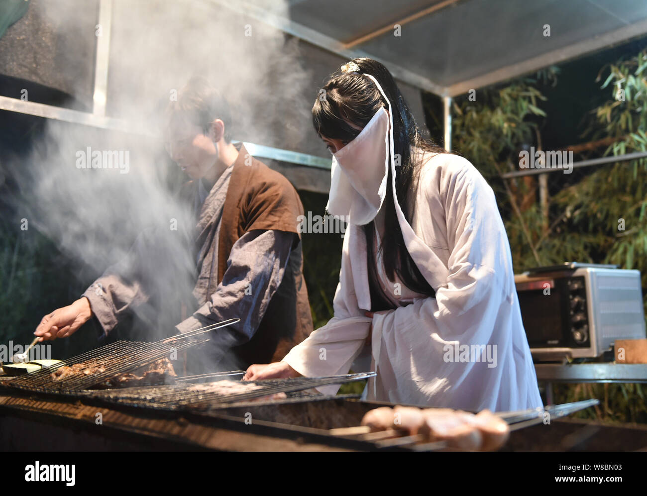 Chinese waiter and waitress wearing ancient Chinese costumes barbecue ...