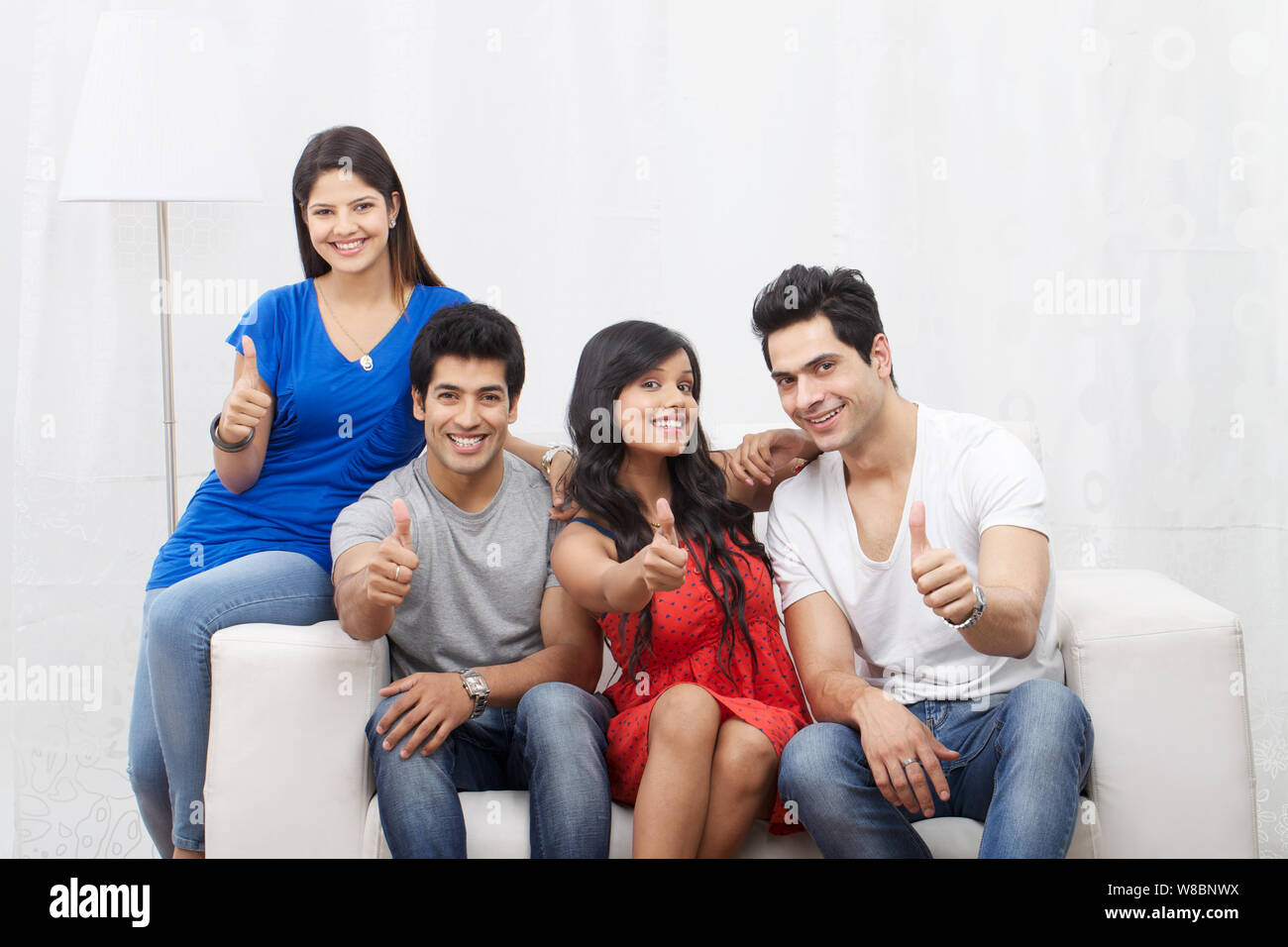 Friends showing thumbs up and smiling Stock Photo - Alamy