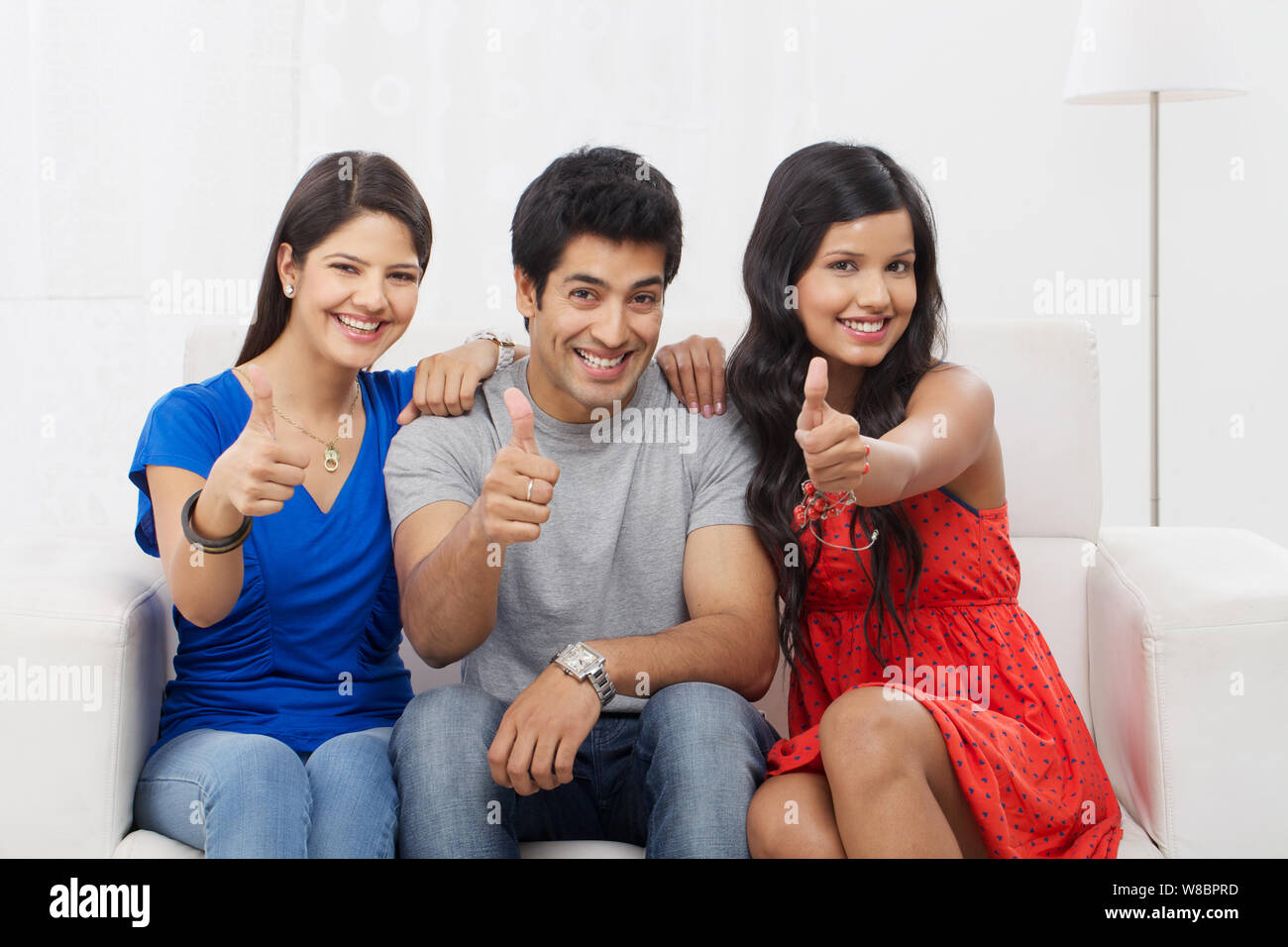 Friends showing thumbs up and smiling Stock Photo - Alamy