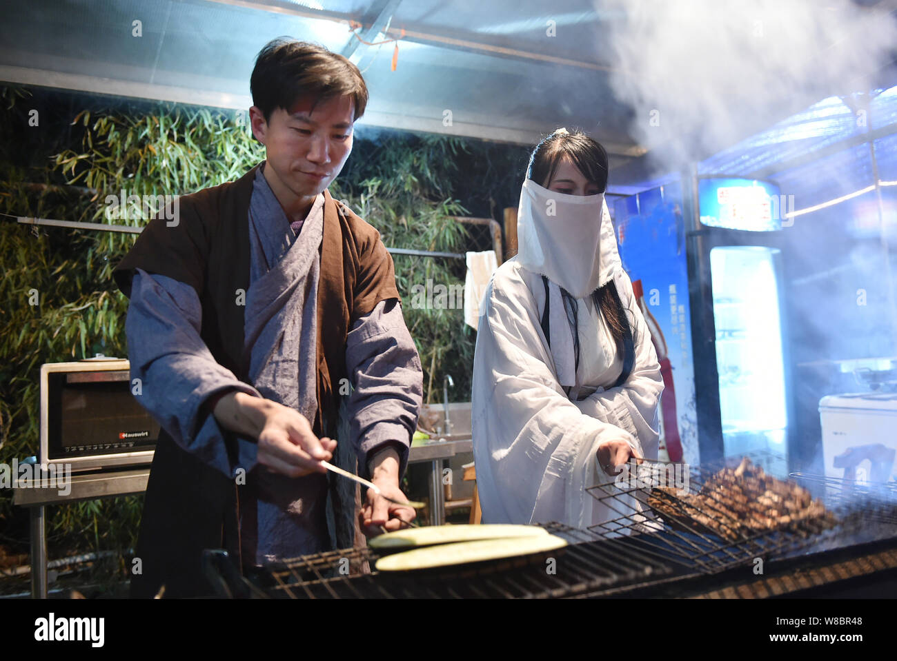 Chinese waiter and waitress wearing ancient Chinese costumes barbecue ...