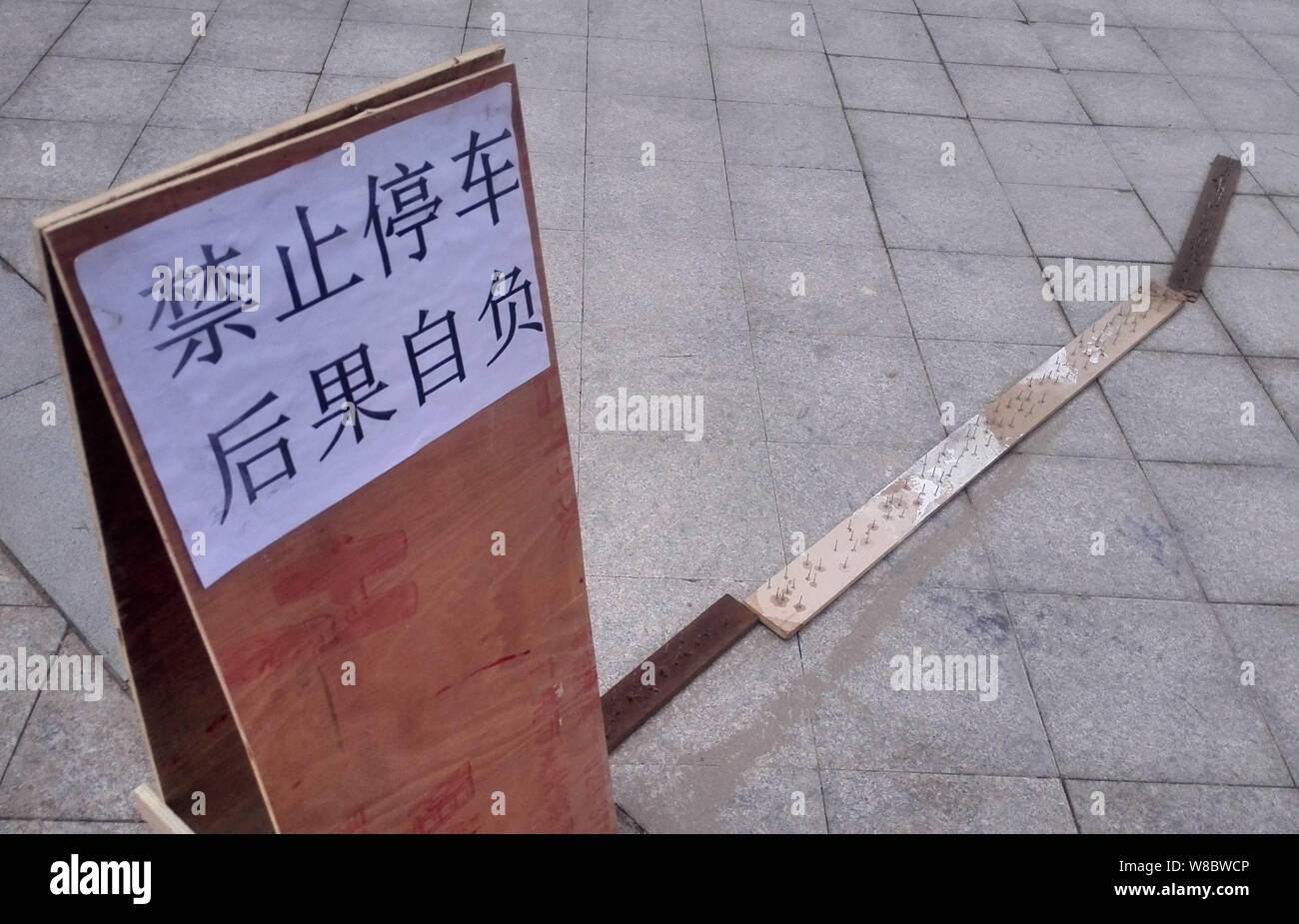 Nail planks and a warning sign are placed on the ground to prevent from ...