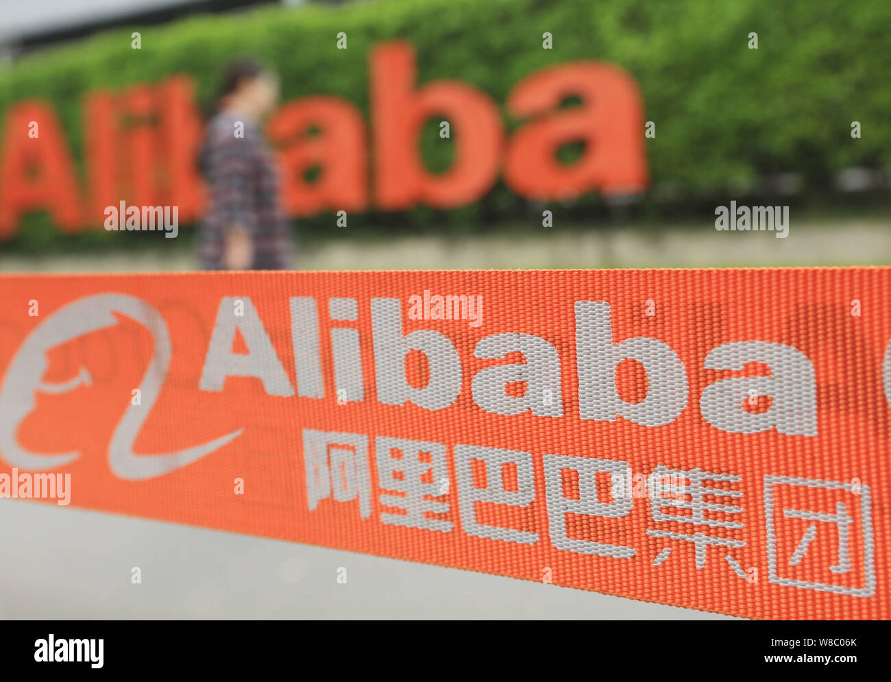 --FILE--A Chinese employee walks past a logo of Alibaba at the ...