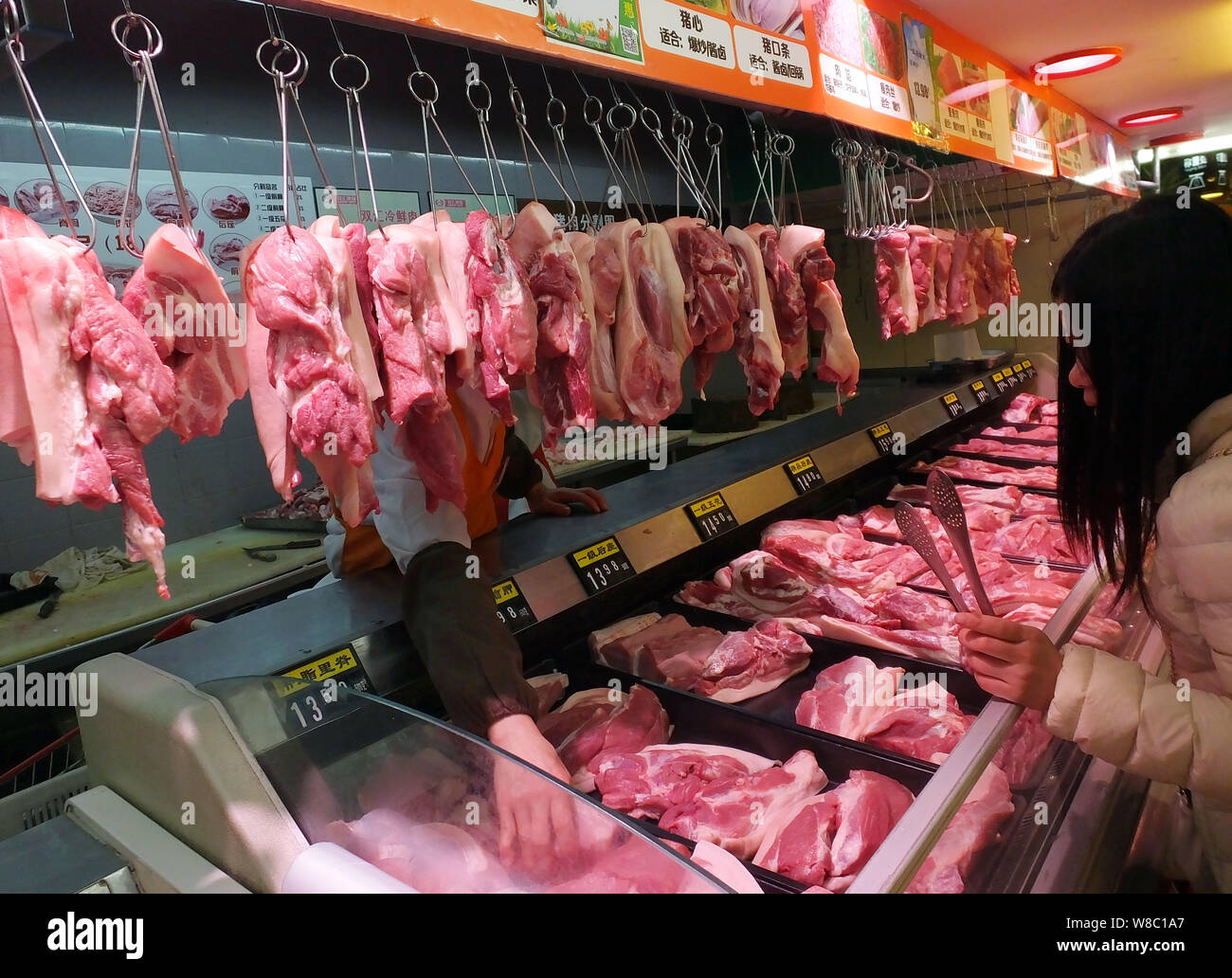 A Chinese customer buys pork at a supermarket in Yichang city, central ...