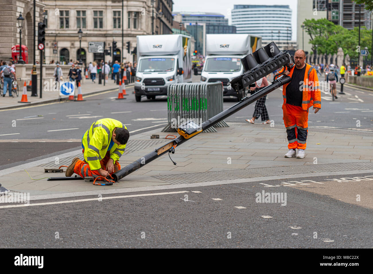 Workers replacing a traffic light signal removed to allow the passage ...