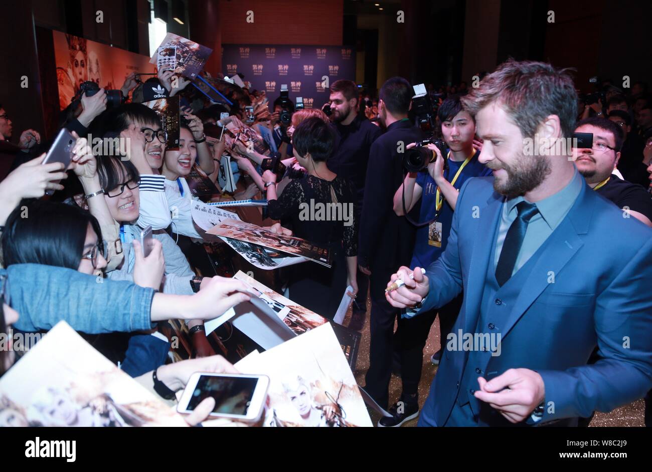 Australian actor Chris Hemsworth, right, signs autographs for fans as ...