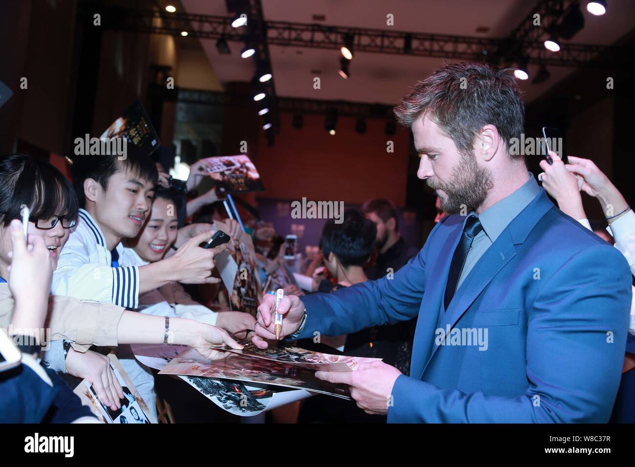 Australian actor Chris Hemsworth, right, signs autographs for fans as ...