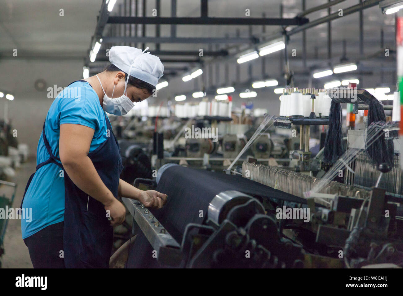 A female Chinese worker sews clothes at a garment factory in Guangzhou ...