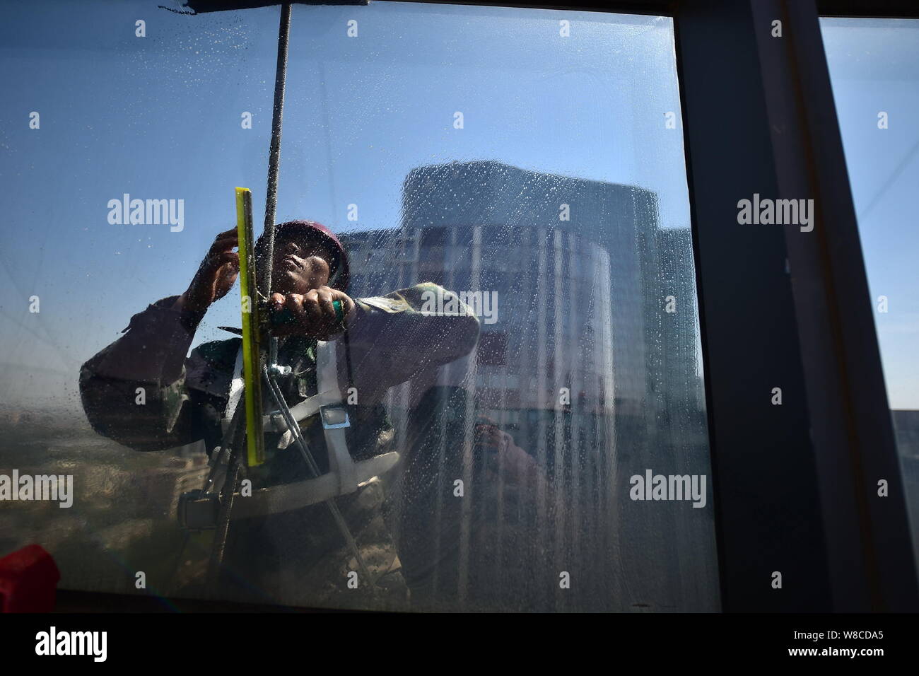 A Chinese migrant worker cleans the exterior window of a high-rise ...