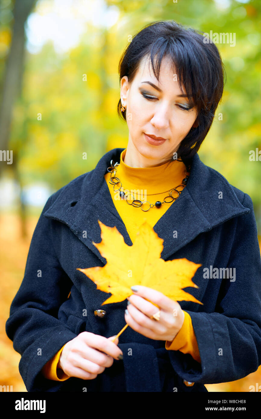 Beautiful woman posing with yellow leaves in autumn city park, fall ...