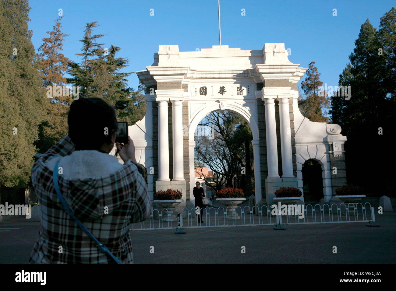 --FILE--A pedestrian takes photos of a gate of Tsinghua University in ...
