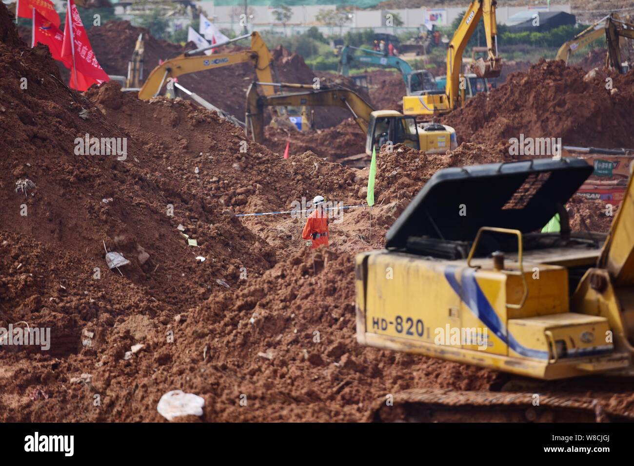 Excavators are used to dig through mud at the site of the landslide ...