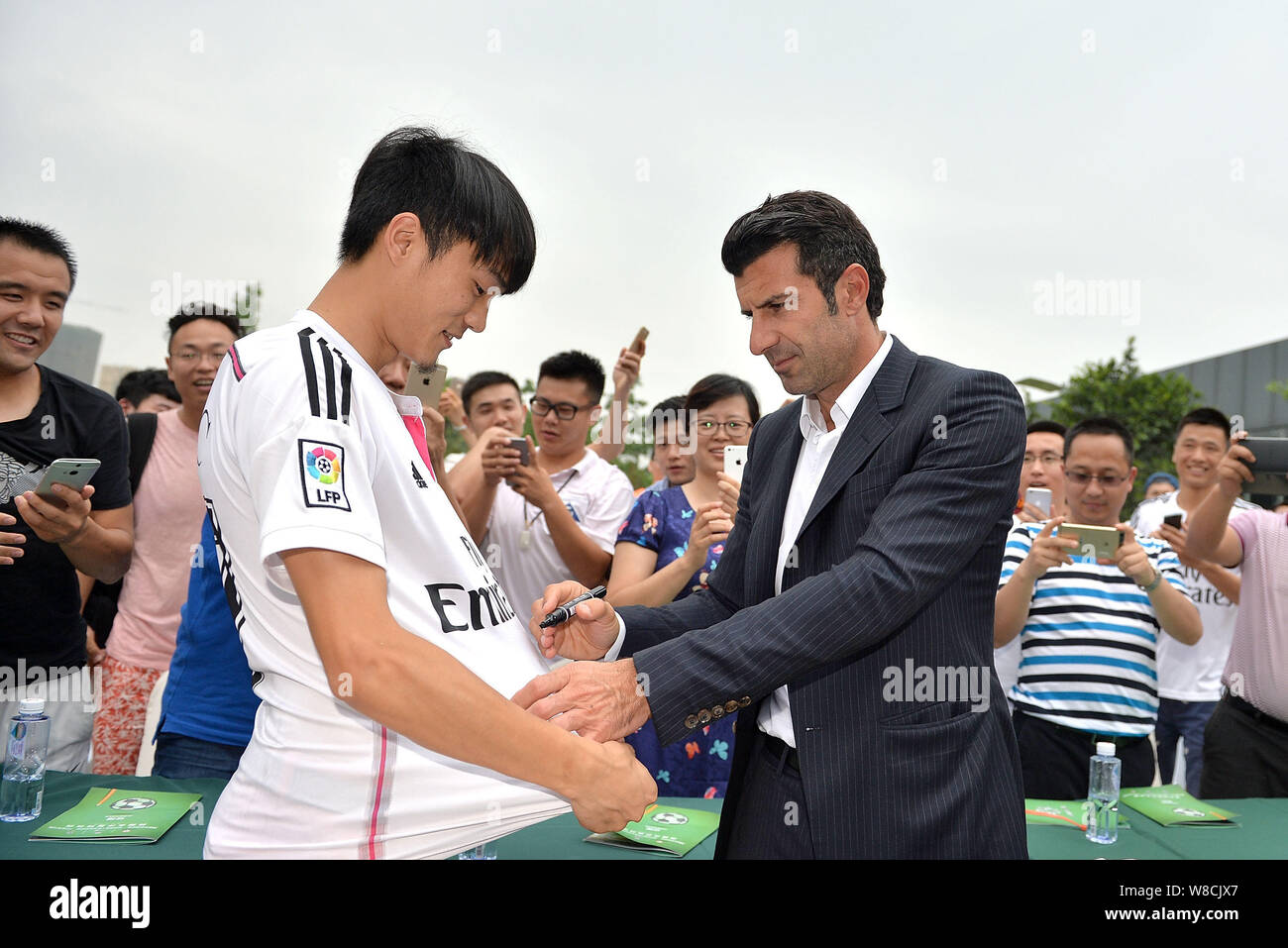Portuguese football star Luis Figo, right, signs an autograph for a fan ...