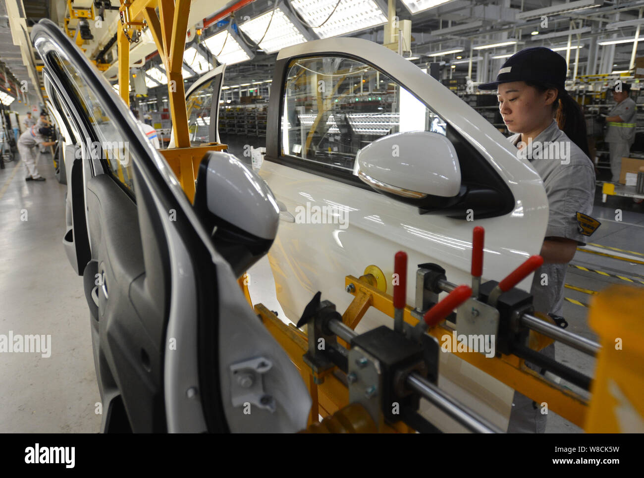 --FILE--A female Chinese worker assembles a car on the assembly line at ...