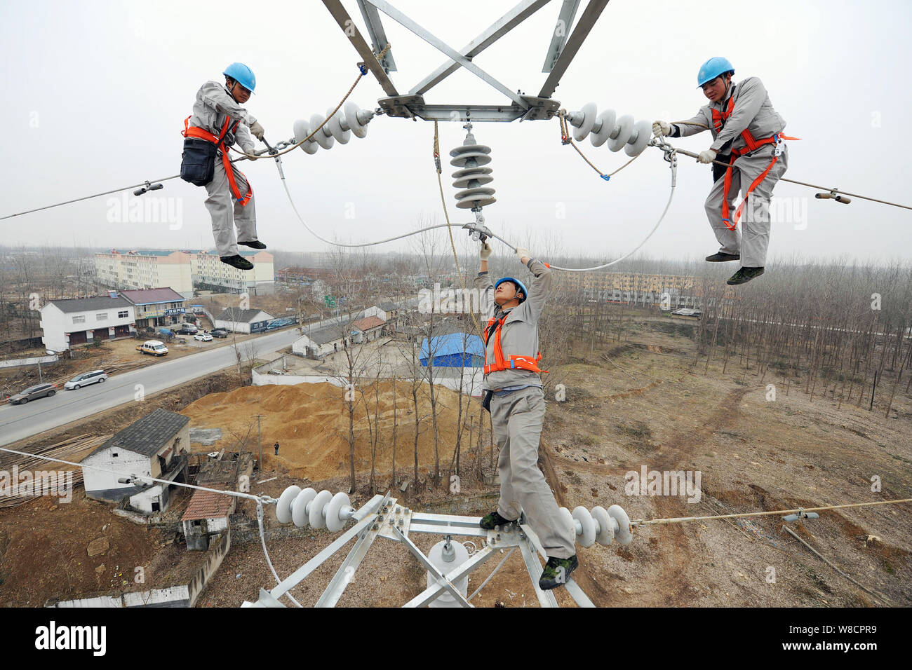 --FILE--Chinese electricians mount high-voltage power lines on a pylon ...