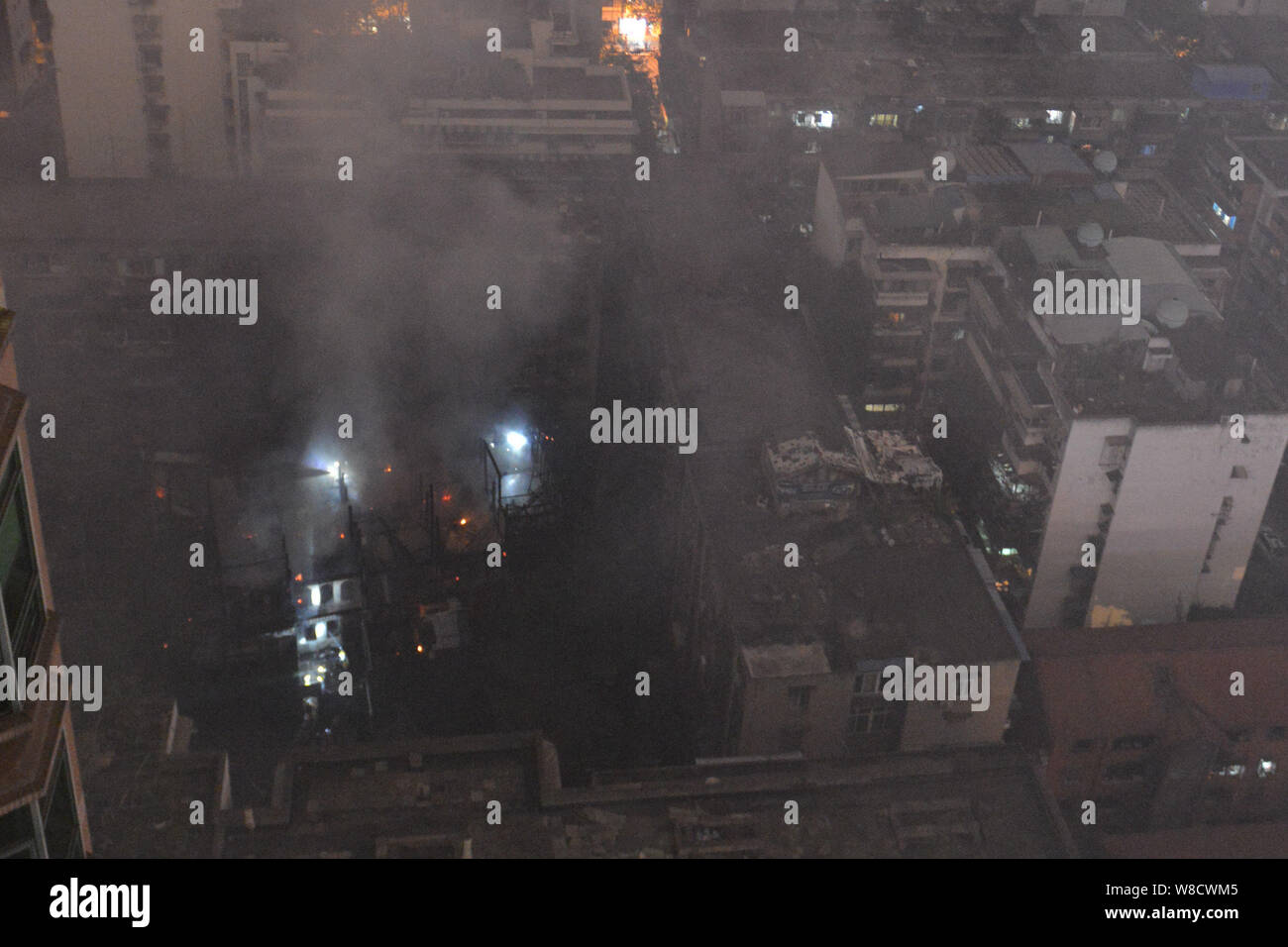 Smoke rises from the debris of a burnt-out old apartment building at a ...