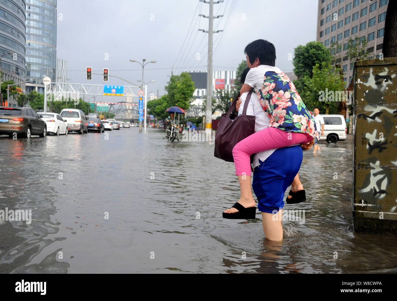 A pedestrian carrying his mother on a flooded road after heavy rain ...