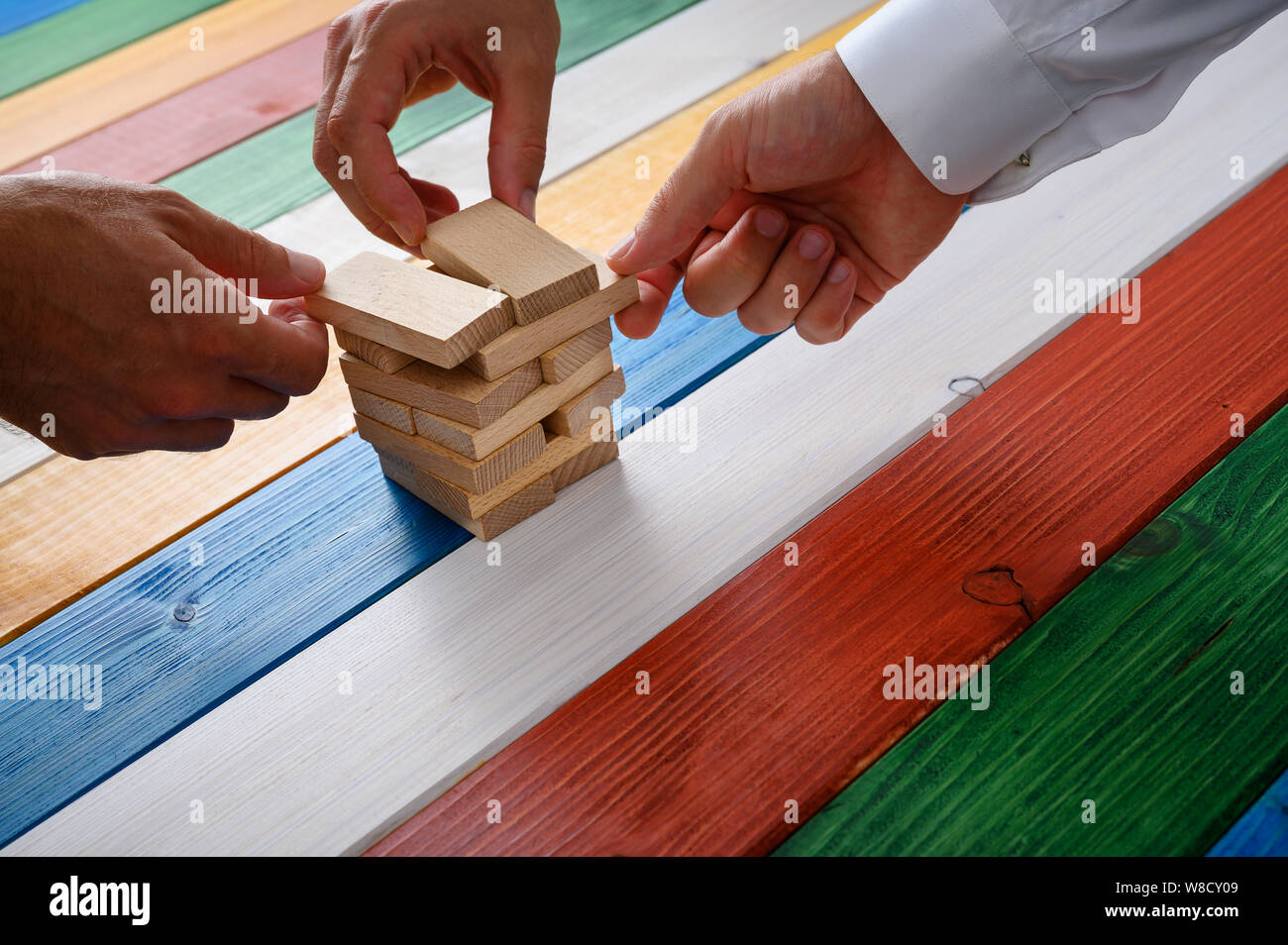 Hands of three businessmen working together to make a stack of wooden ...