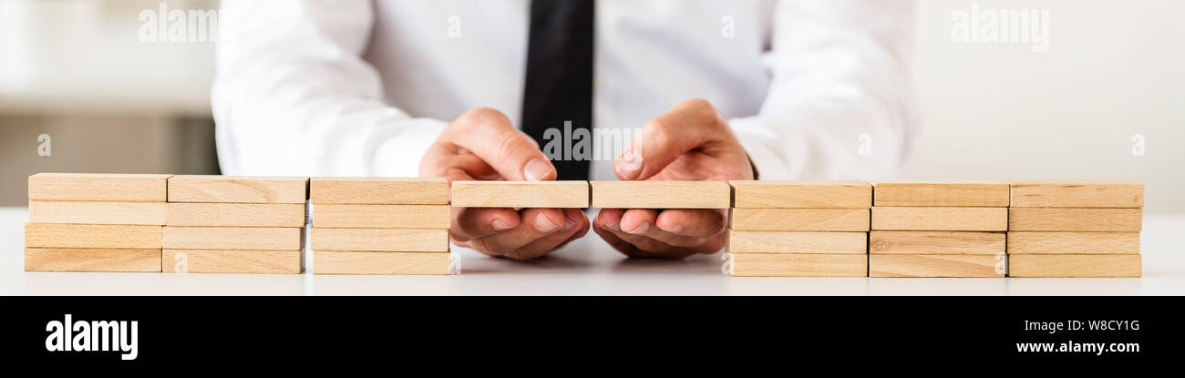 Wide view image of businessman making a connection between two stack of ...