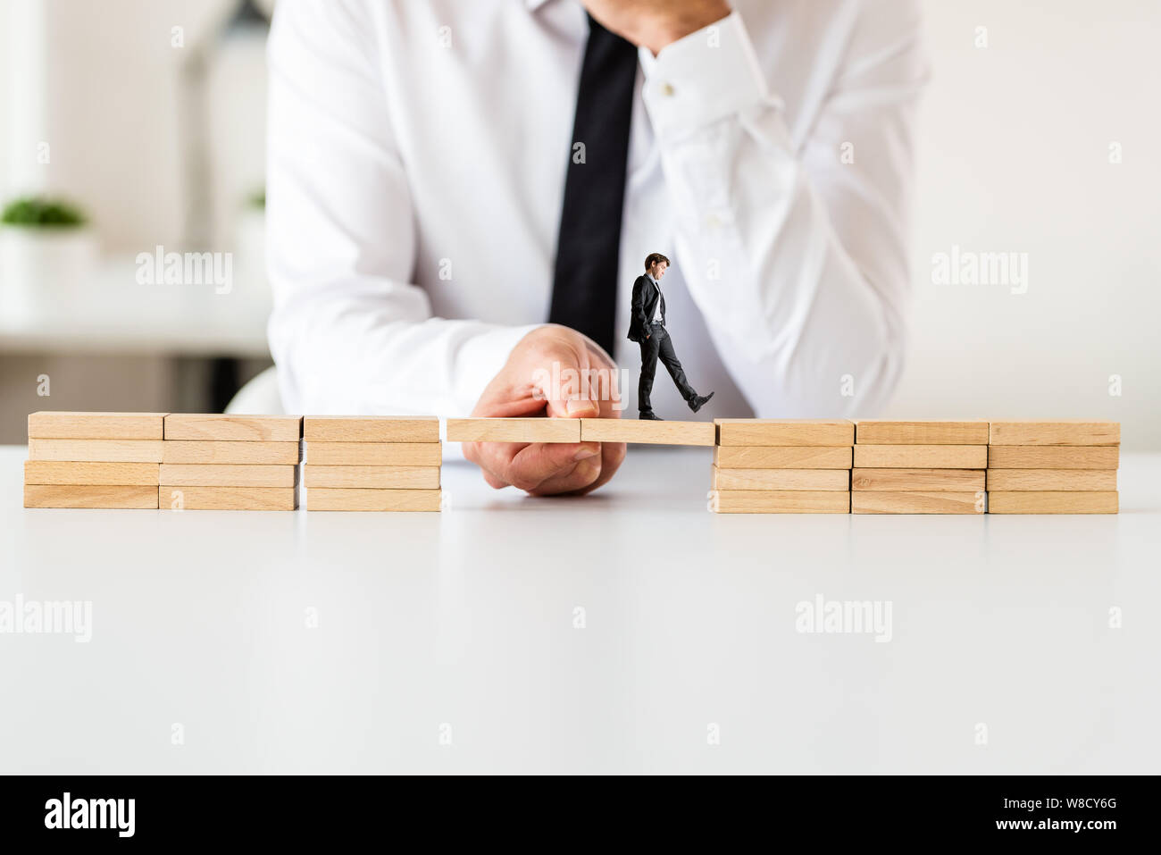 Businessman making a bridge between two stacks of wooden pegs for the ...