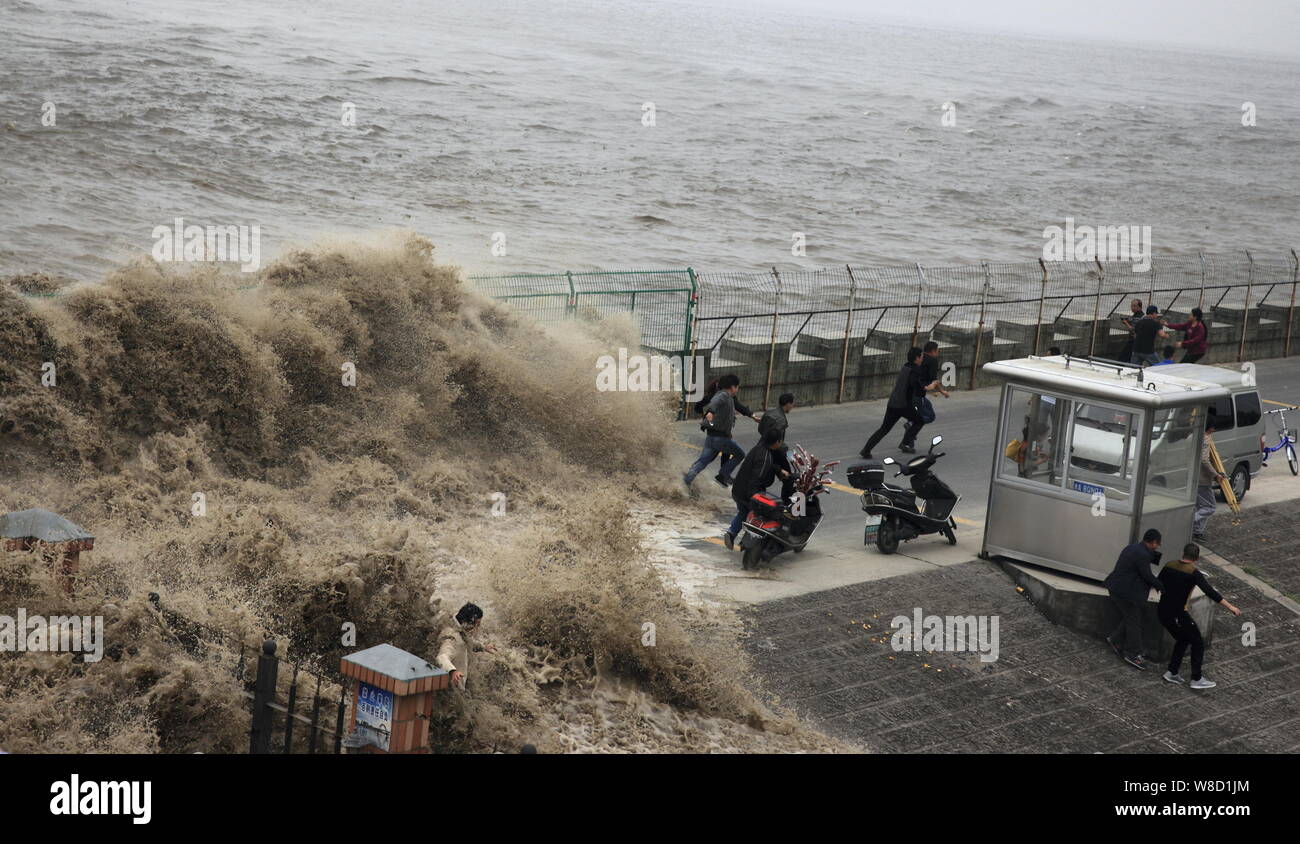 People run away as tidal bores from the Qiantang River surge over the ...