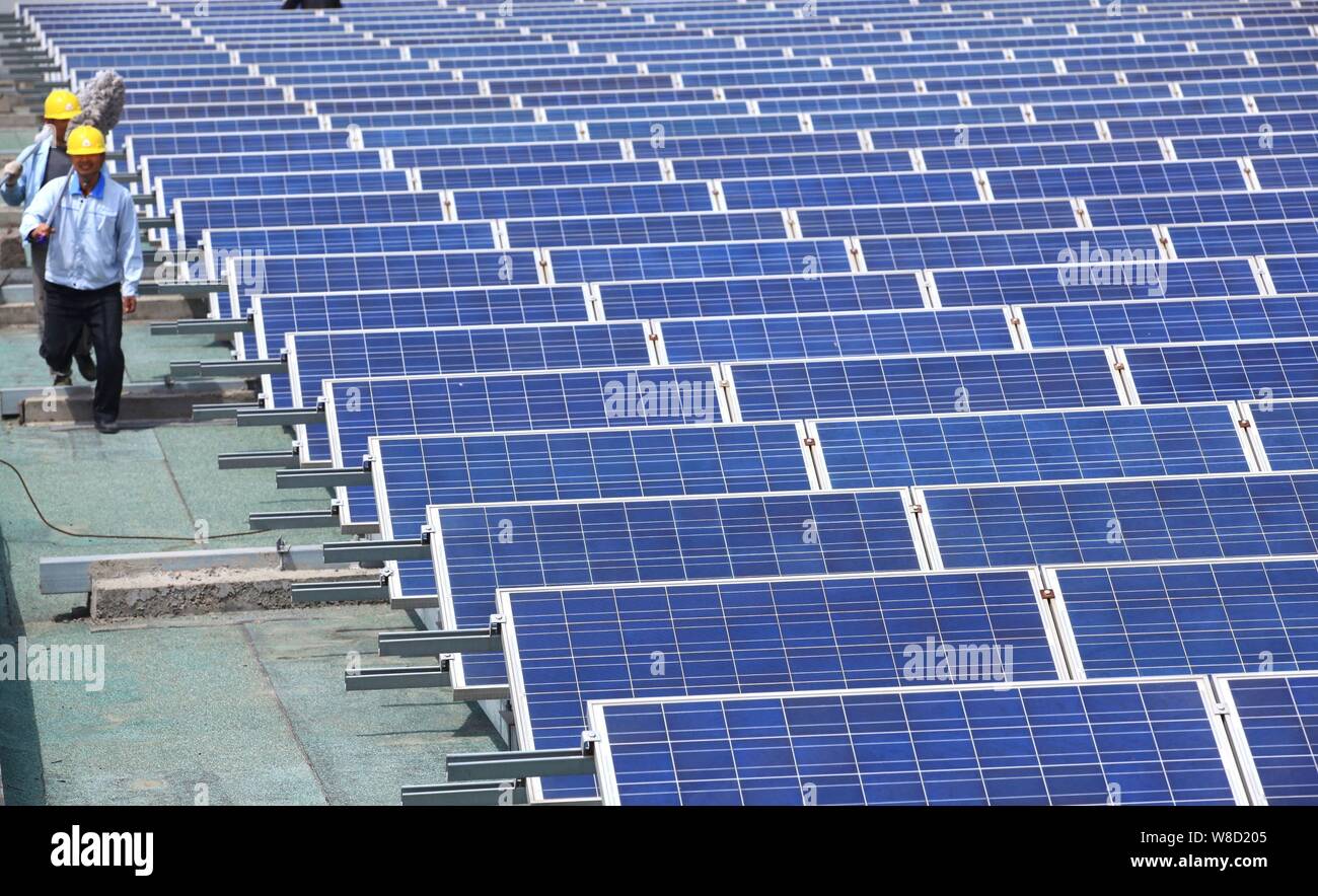 --FILE--Chinese workers walk past solar panels on the rooftop of a ...