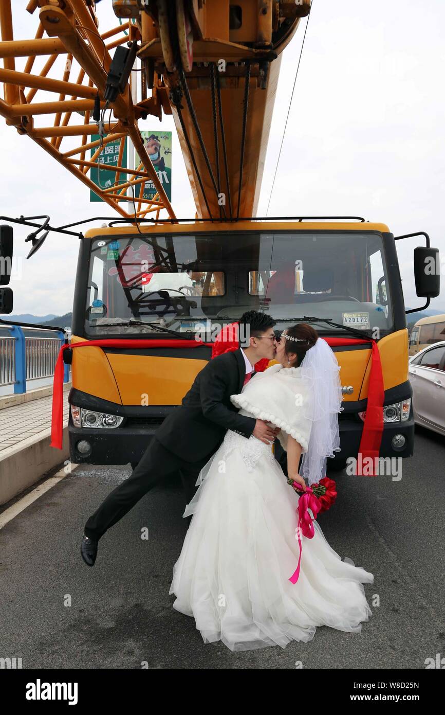 Chinese groom Xie Jiangjian, left, kisses his bride in front of a crane ...