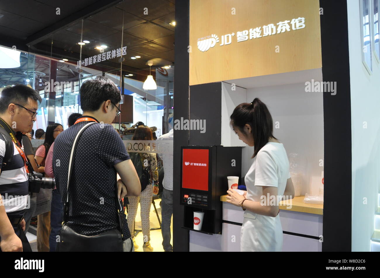 A Chinese employee makes milk tea for visitors at a "JD+ smart milk tea ...
