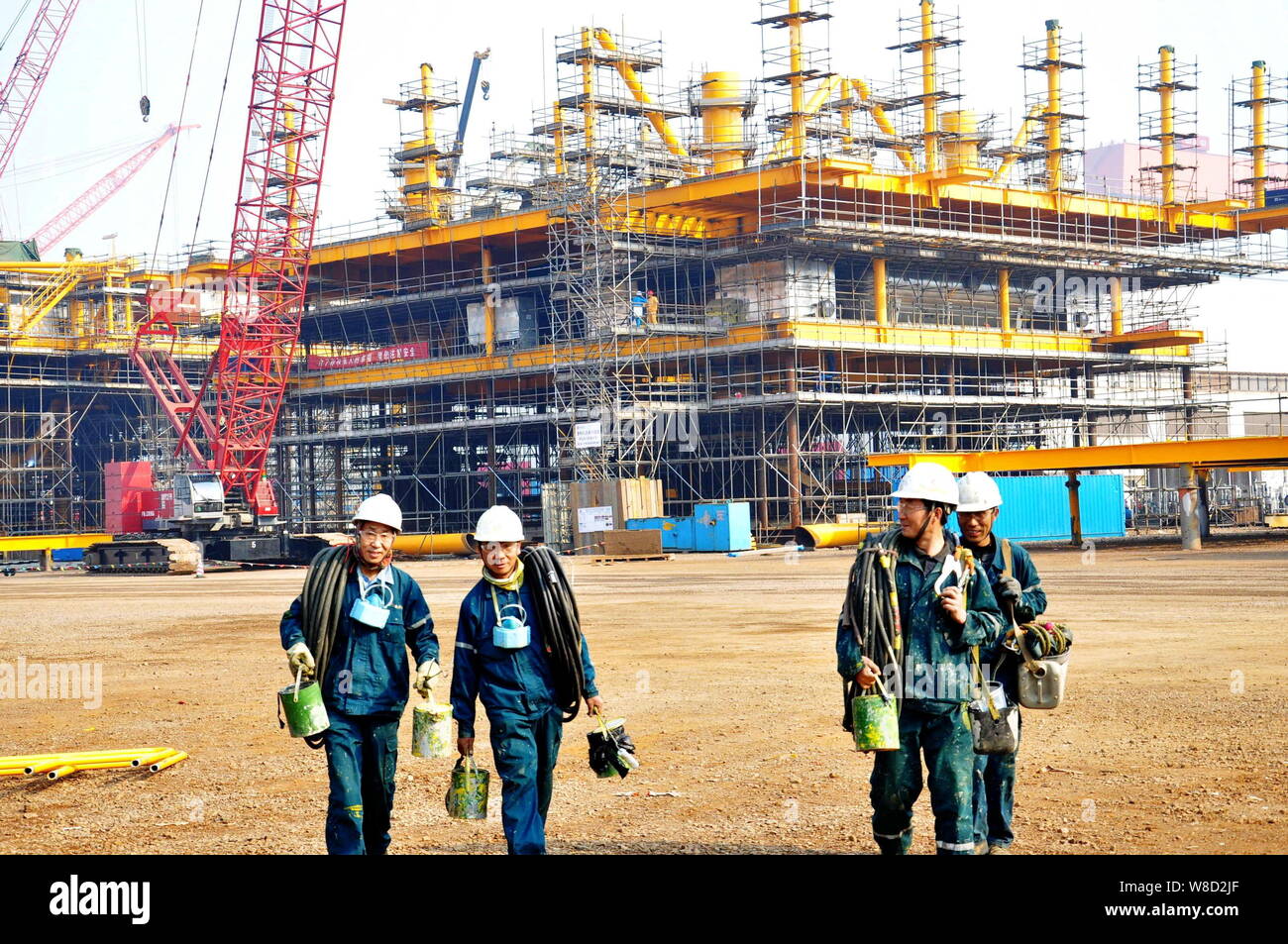 --FILE--Chinese workers walk past an offshore oil rig being built at a ...