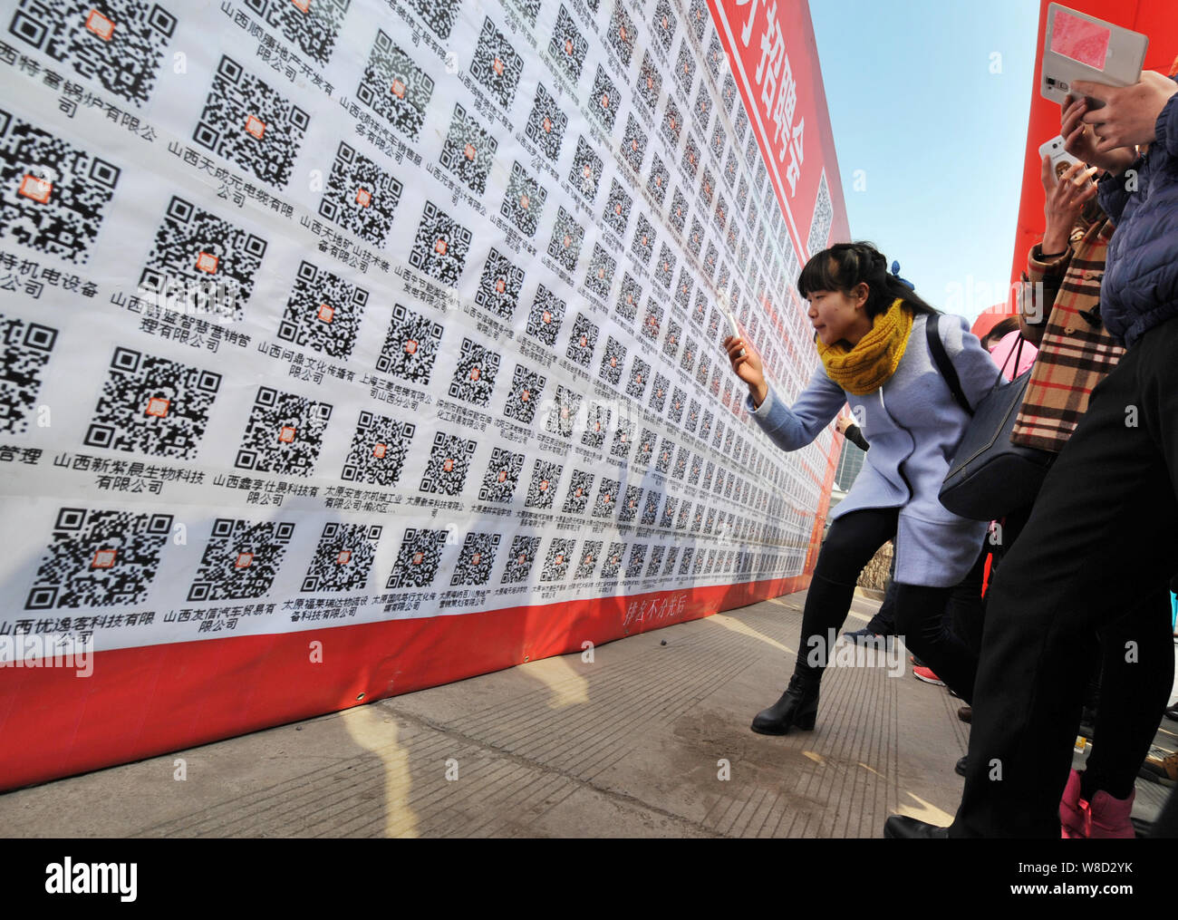 A job seeker scans a QR code on a big billboard of available jobs to ...
