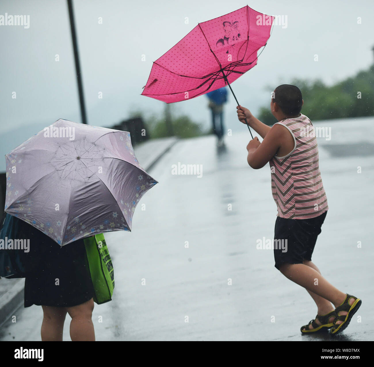 Pedestrians brave strong wind and heavy rain caused by Typhoon Chan-hom ...