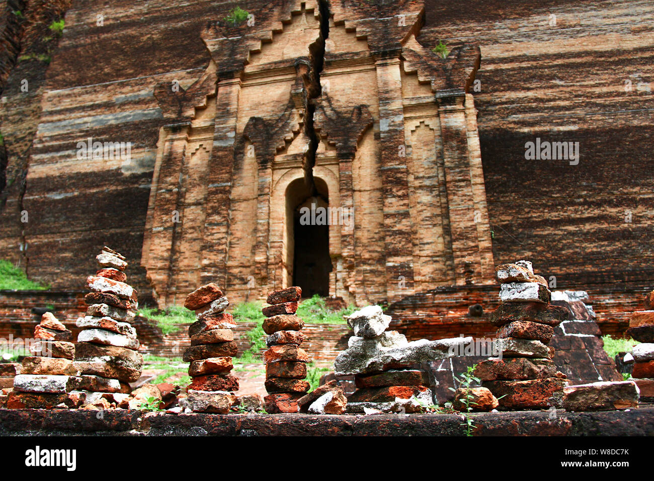 Stacked stones in front of a big entrance with a huge crack of a temple ...