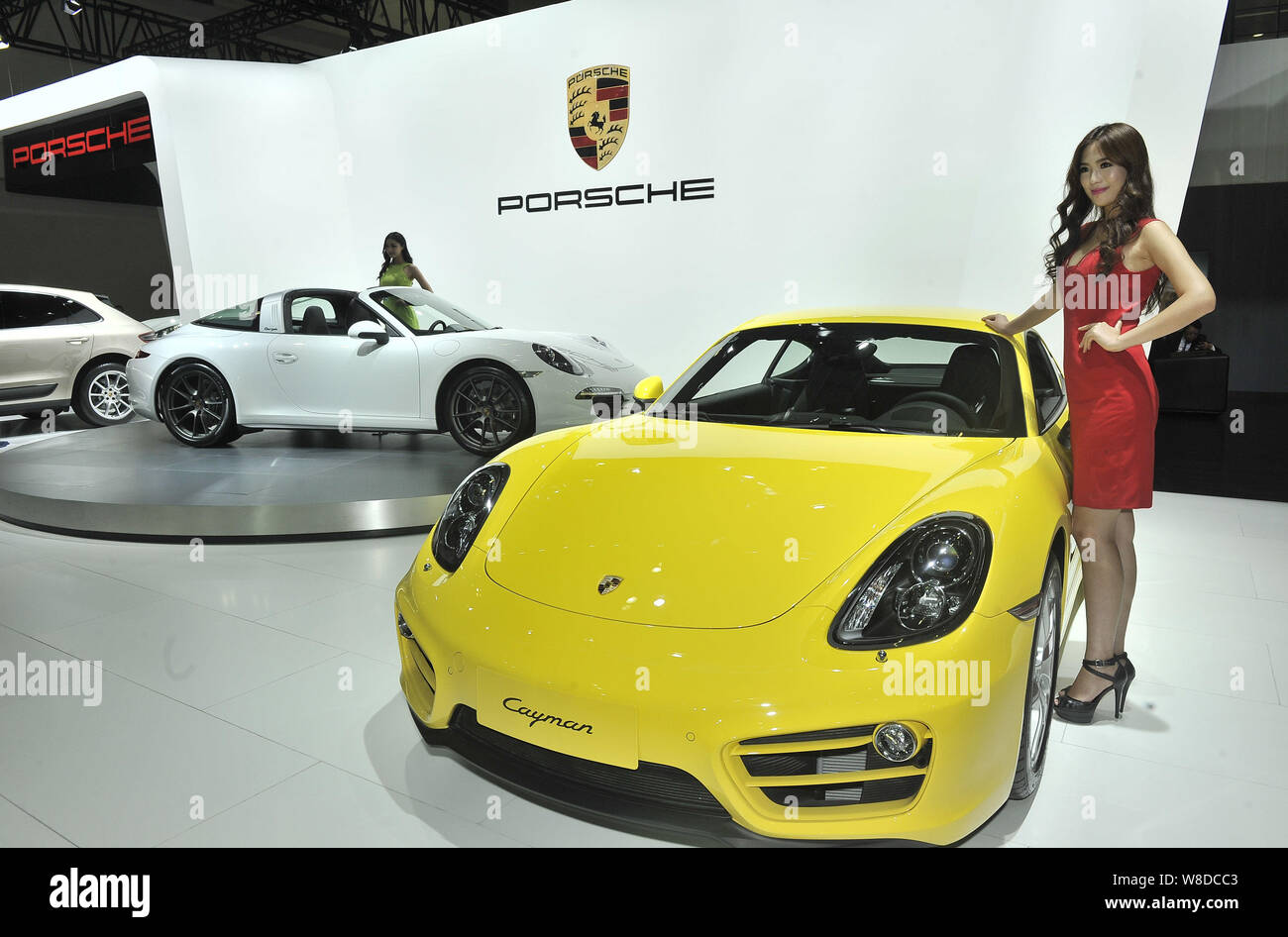 --FILE--Models pose with Porsche sports cars on display at an ...