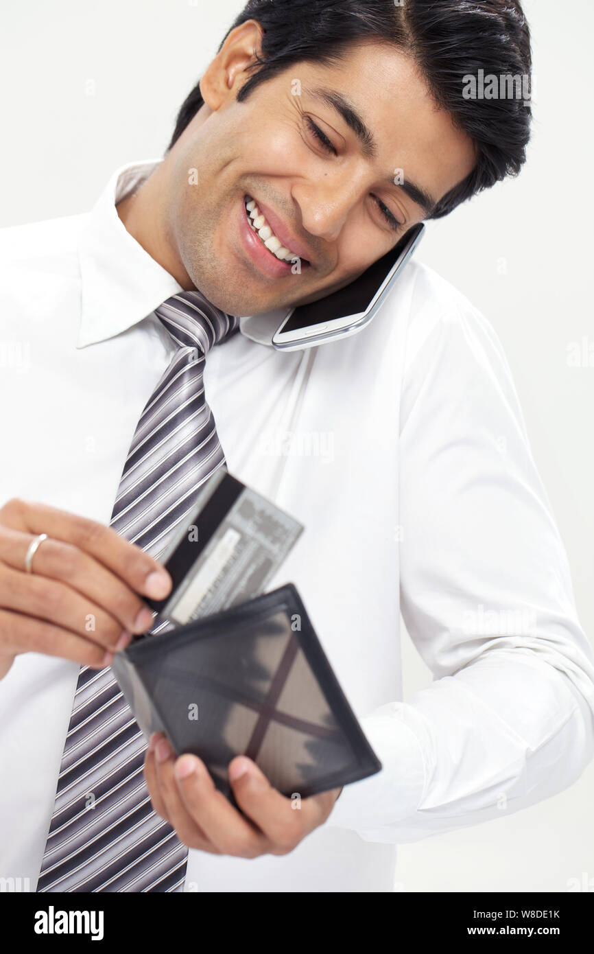 Businessman talking on mobile phone and taking credit card from his ...