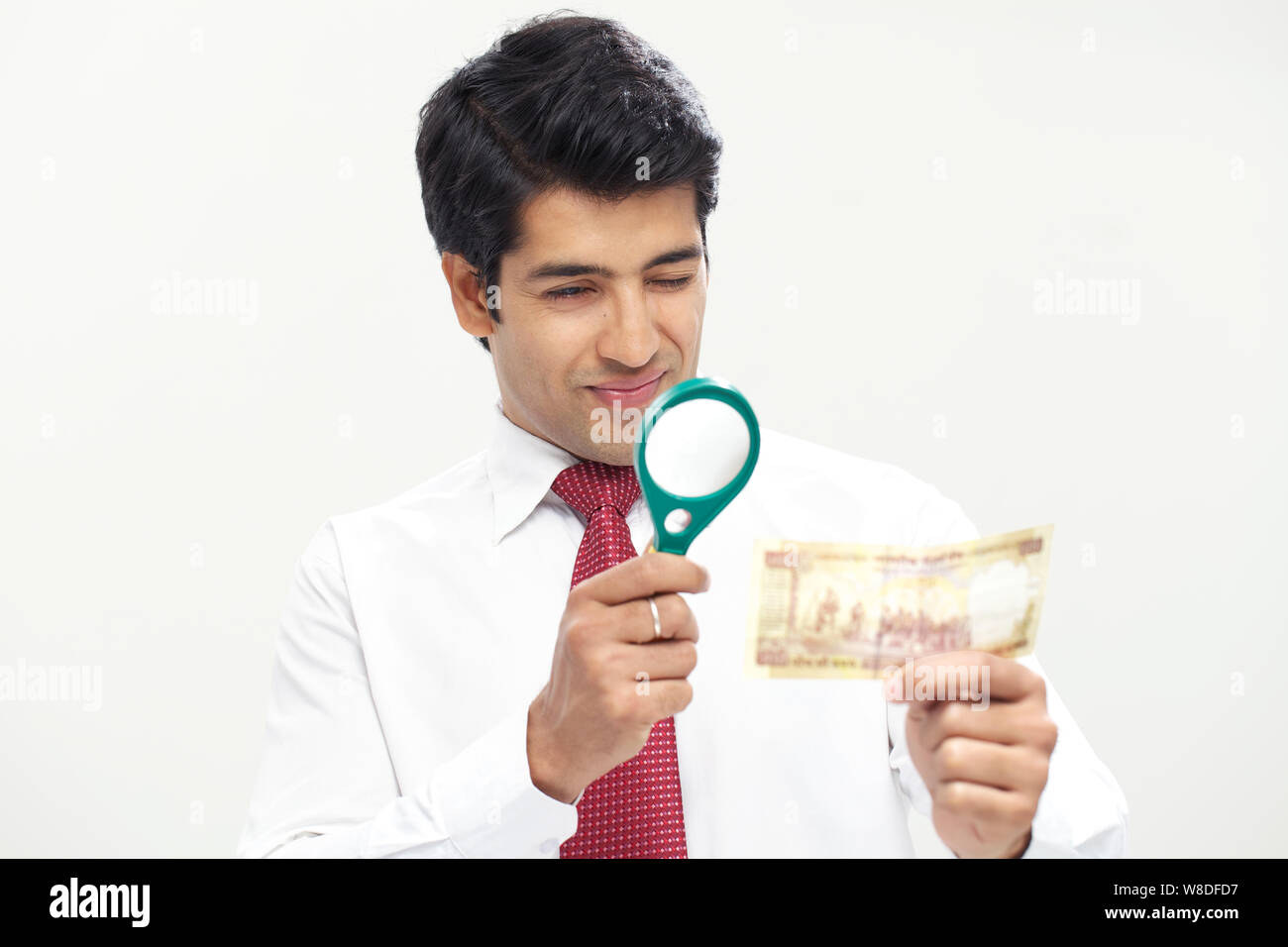 Businessman examining five hundred rupee note banknote with magnifying ...