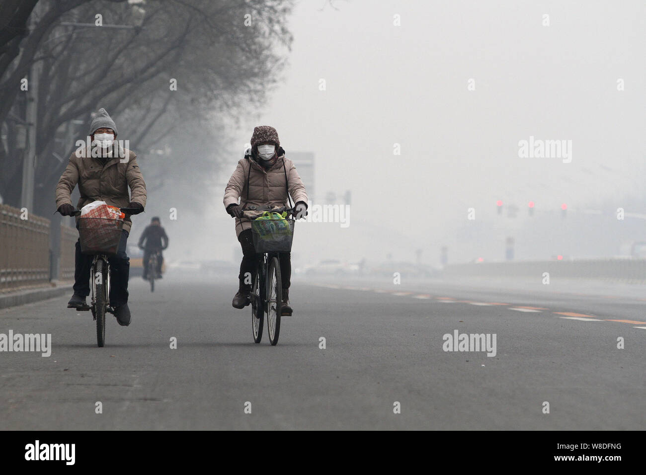 Cyclists wearing face masks ride on a road in heavy smog in Beijing ...